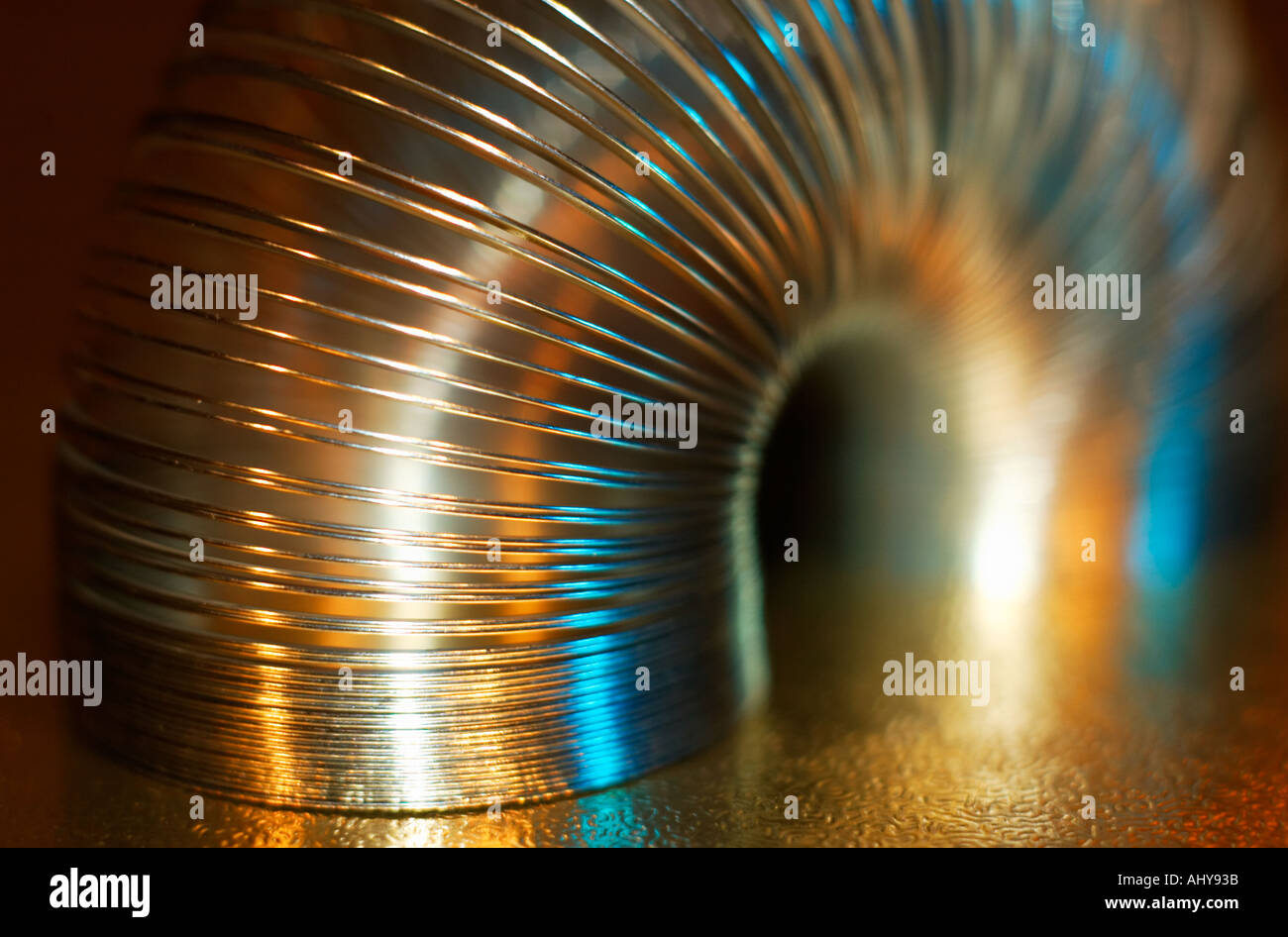 Slinky spring coiled with golden and blue lighting Stock Photo - Alamy