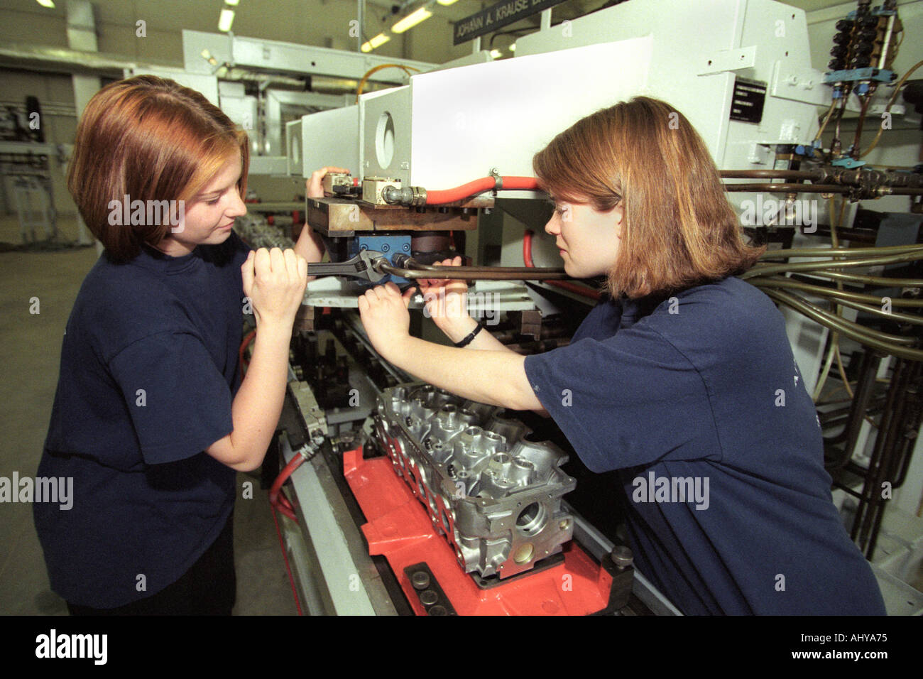 Young women trainees setting up a cylinder head stud runner on a ...