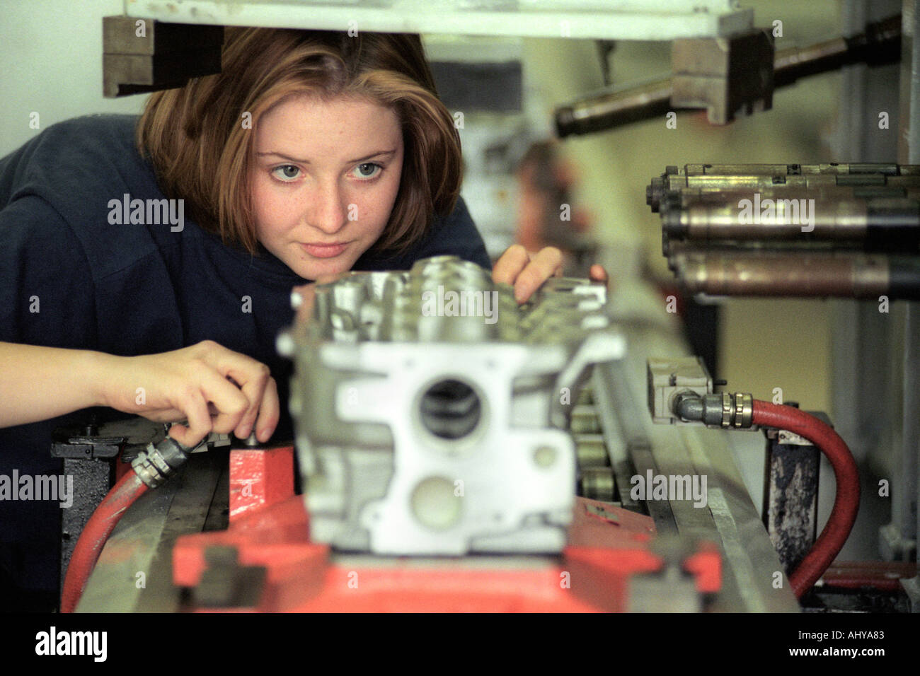 Young woman trainee setting up a cylinder head stud runner on a ...