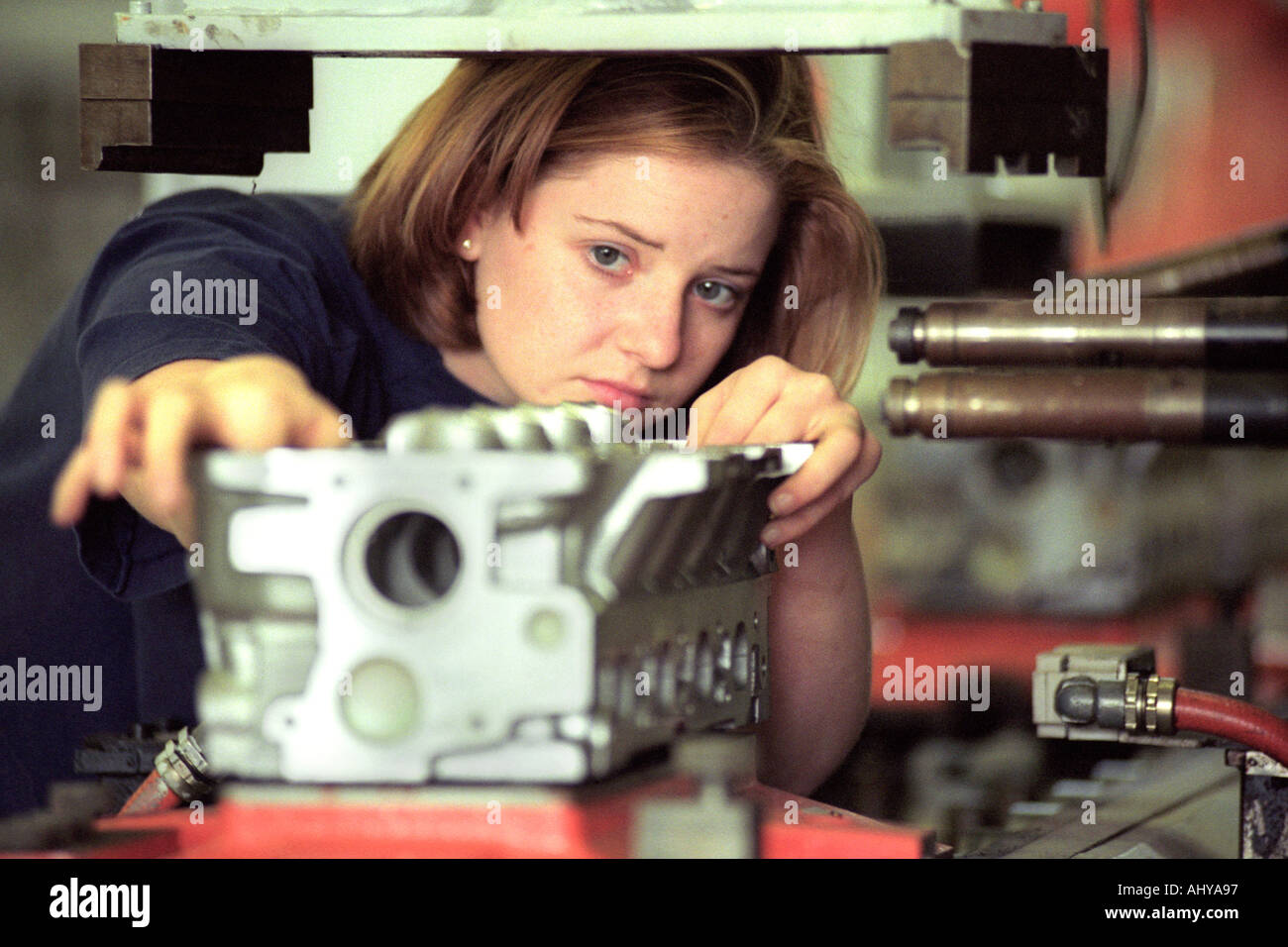Young woman trainee setting up a cylinder head stud runner on a ...