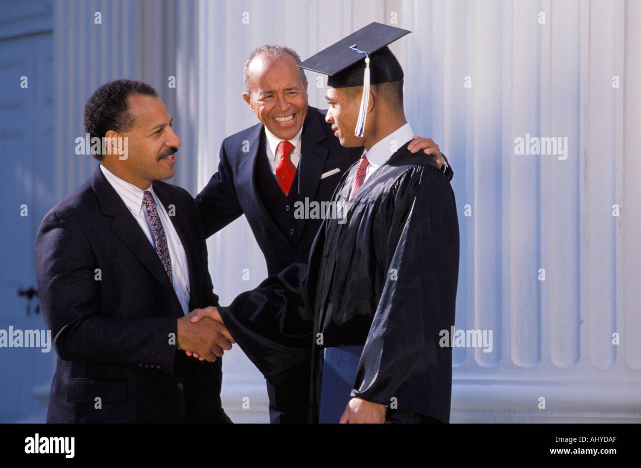 African American father and grandfather concratulating male graduate ...