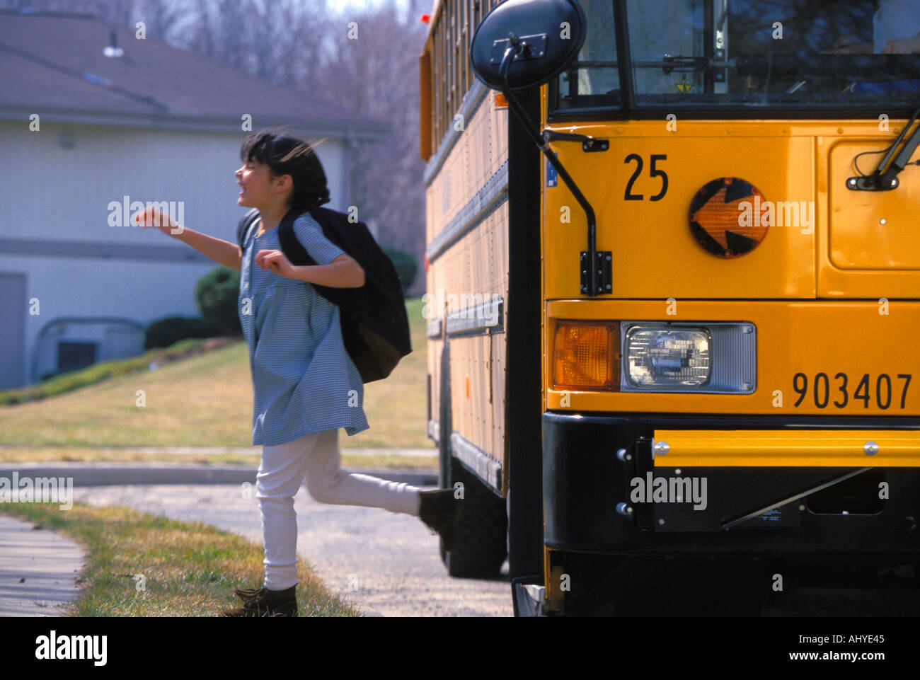 Caucasian girl getting off school bus in the suburban neighborhood ...