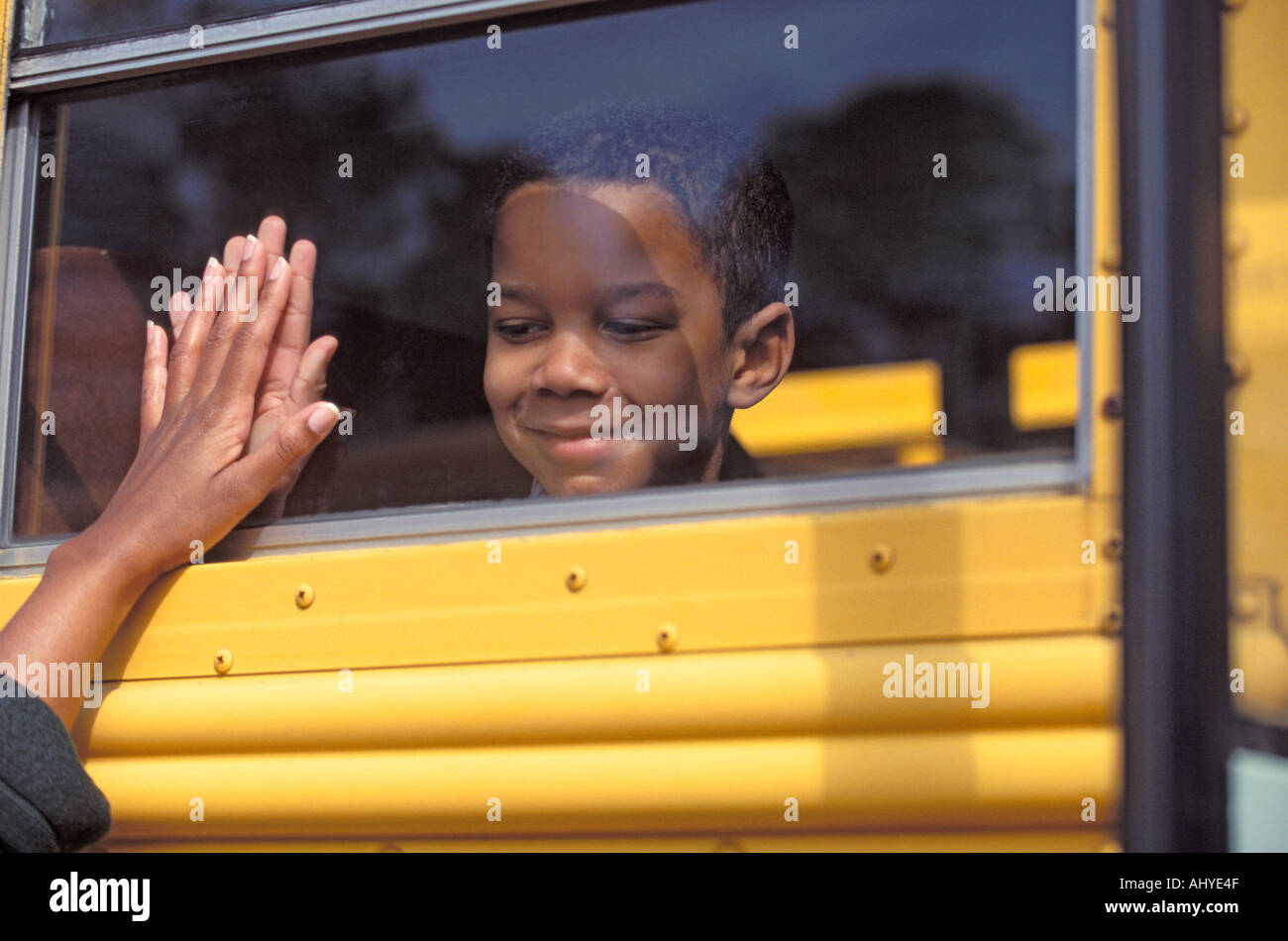 African American male student saying goodbye to Mom from school bus ...