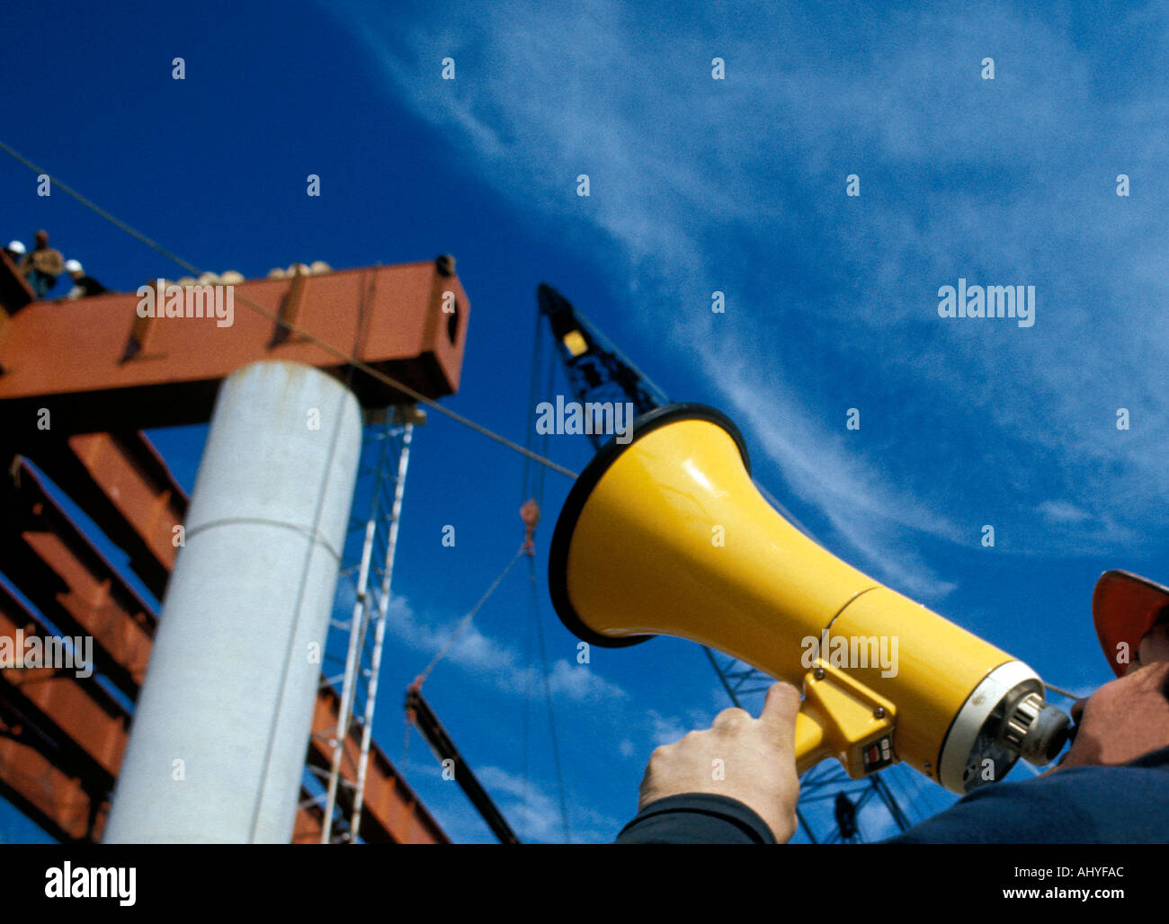 Construction foreman using megaphone giving instructions to workers ...