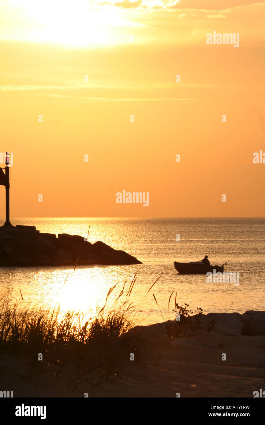 Fishing boat heading into harbor at sunset Stock Photo - Alamy