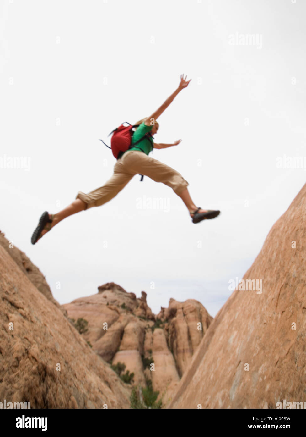 Woman jumping over rock formation Stock Photo - Alamy