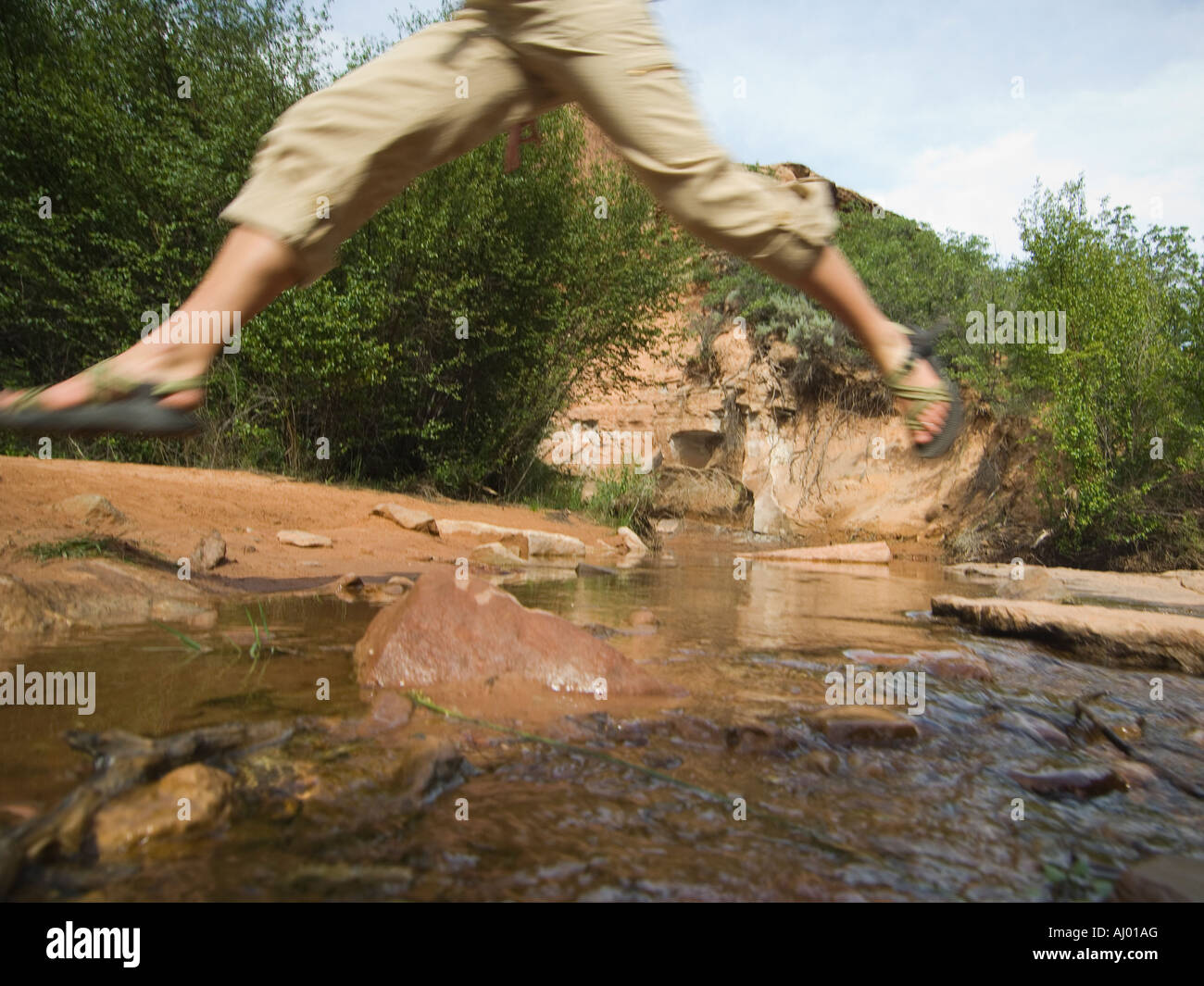 Woman jumping over stream Stock Photo - Alamy