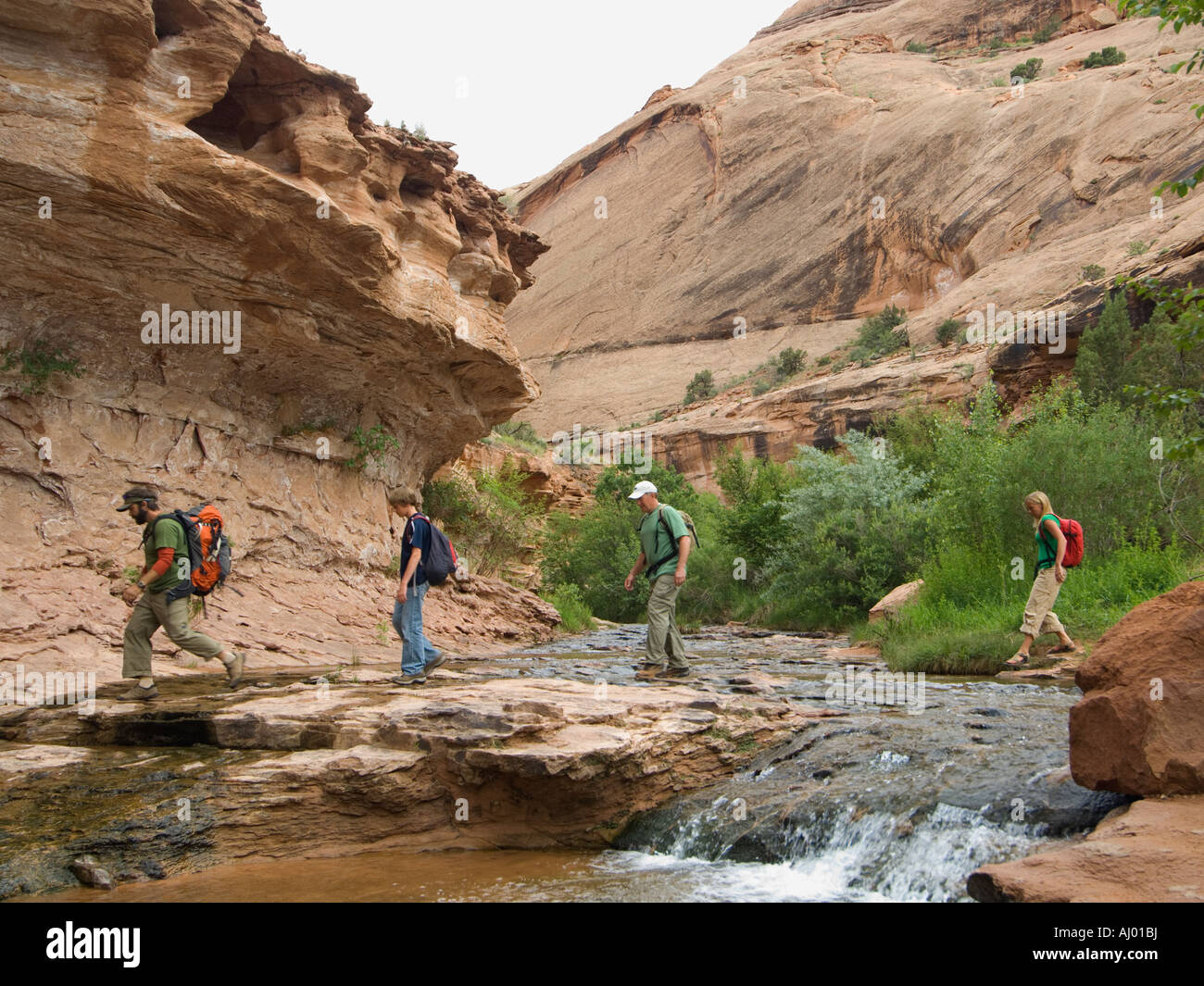 People hiking over stream Stock Photo - Alamy