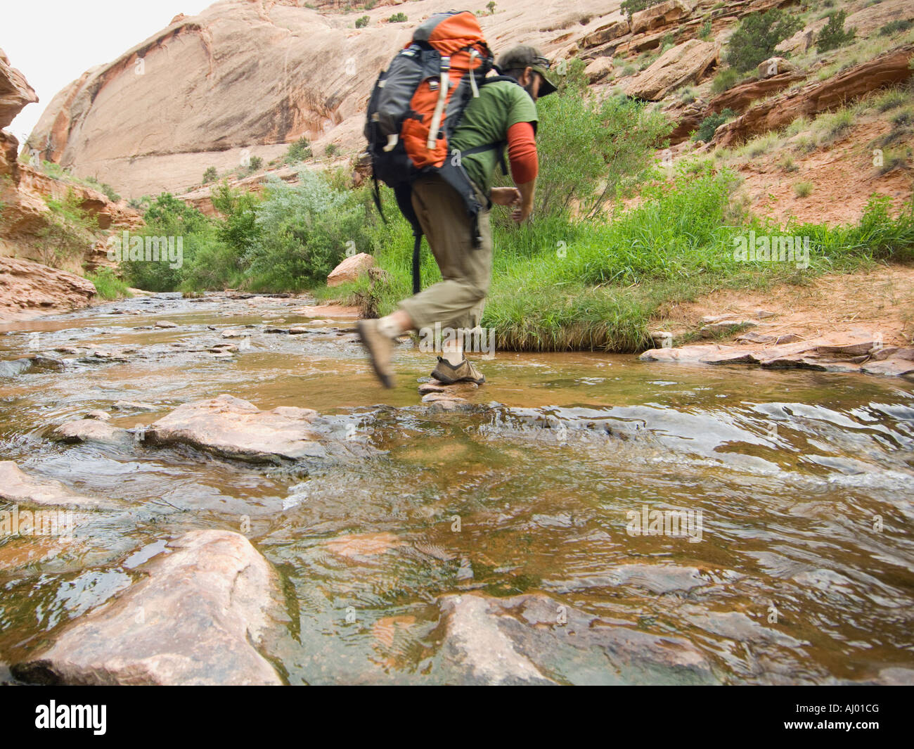 Man hiking through stream Stock Photo - Alamy