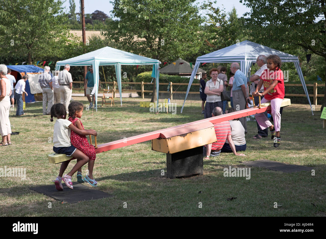 Children playing on a see saw at summer fete Suffolk England Stock ...