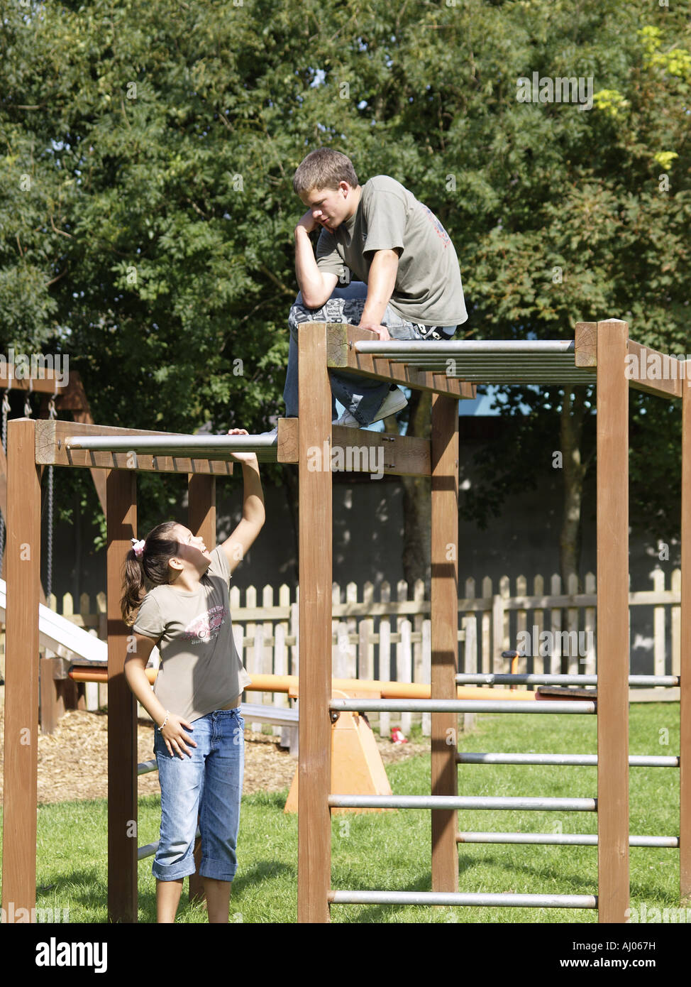 Two teenagers playing on the monkey bars in a children's playground ...