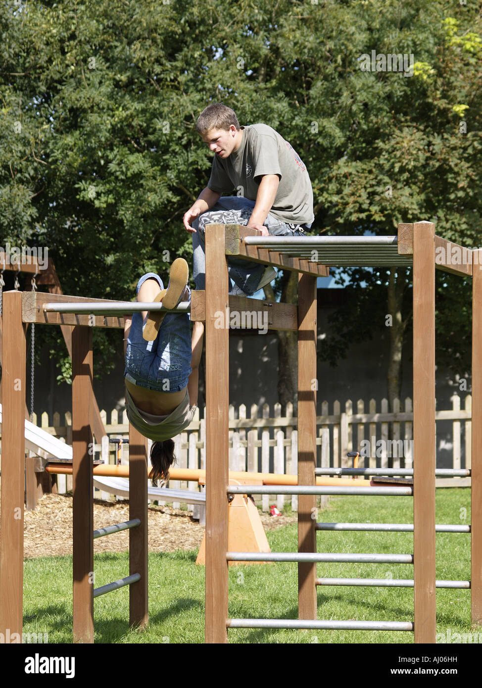Two teenagers playing on the monkey bars in a children's playground ...