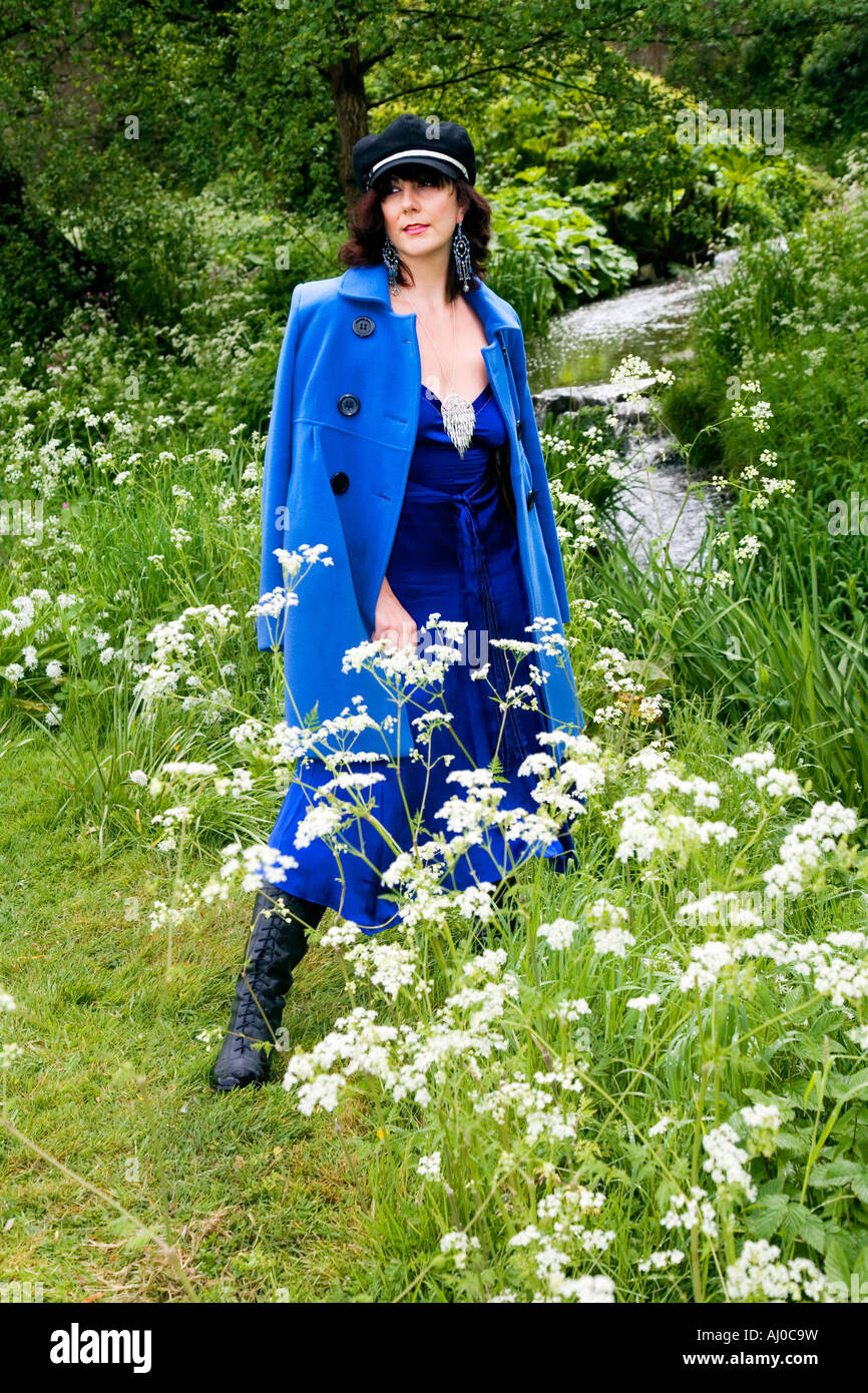 A girl stands in front of a twisting stream in a woodland setting Stock ...