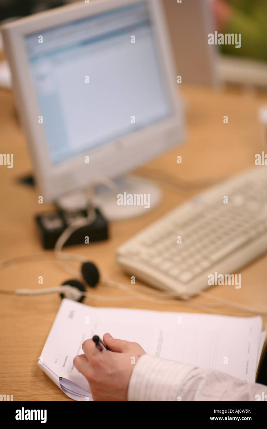 man office worker fills in form by computer screen, on the desk is a ...