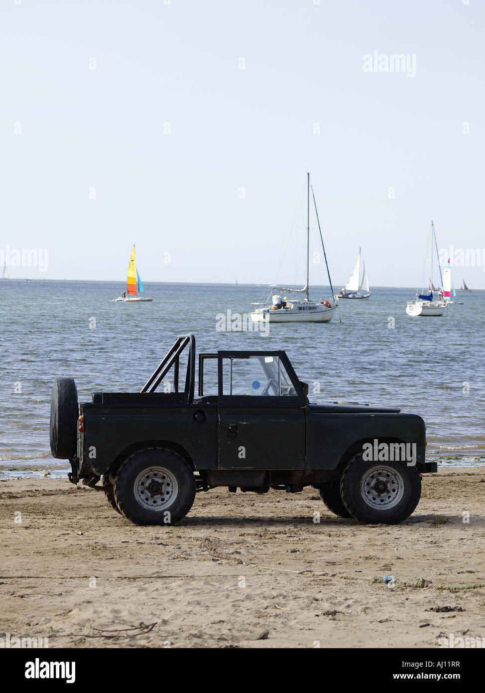 Black, off roading vehicle parked beside the sea on a sandy beach. with ...