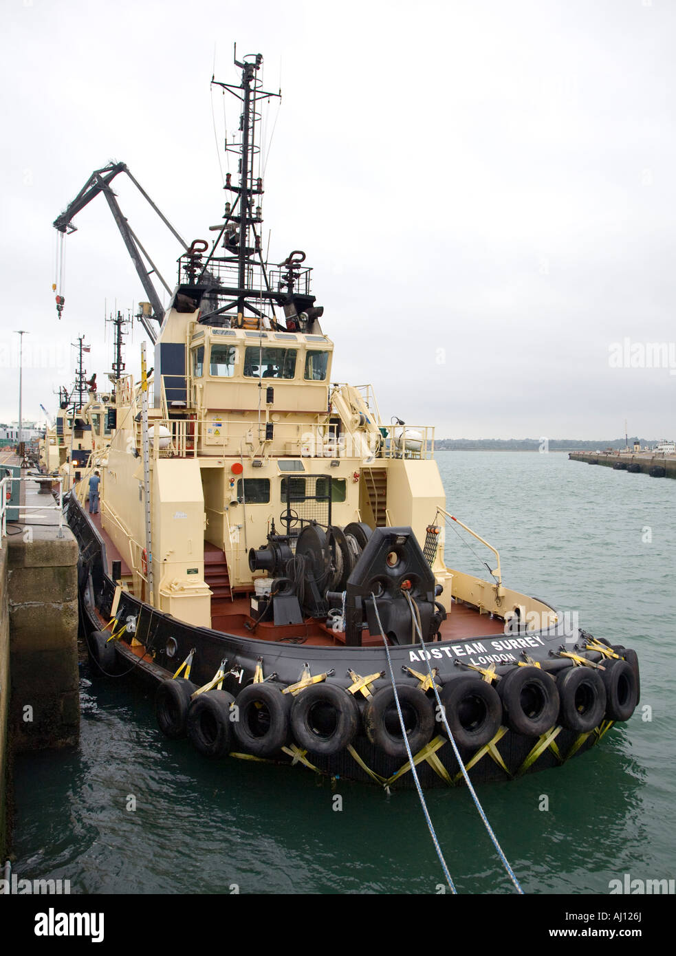 Black and cream tug boat with large floating crane in background Stock ...