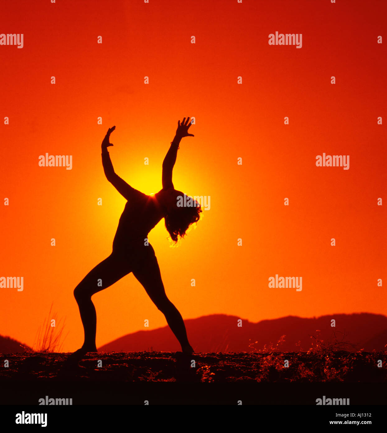 Sunset silhouette of young woman in dramatic pose against the setting ...