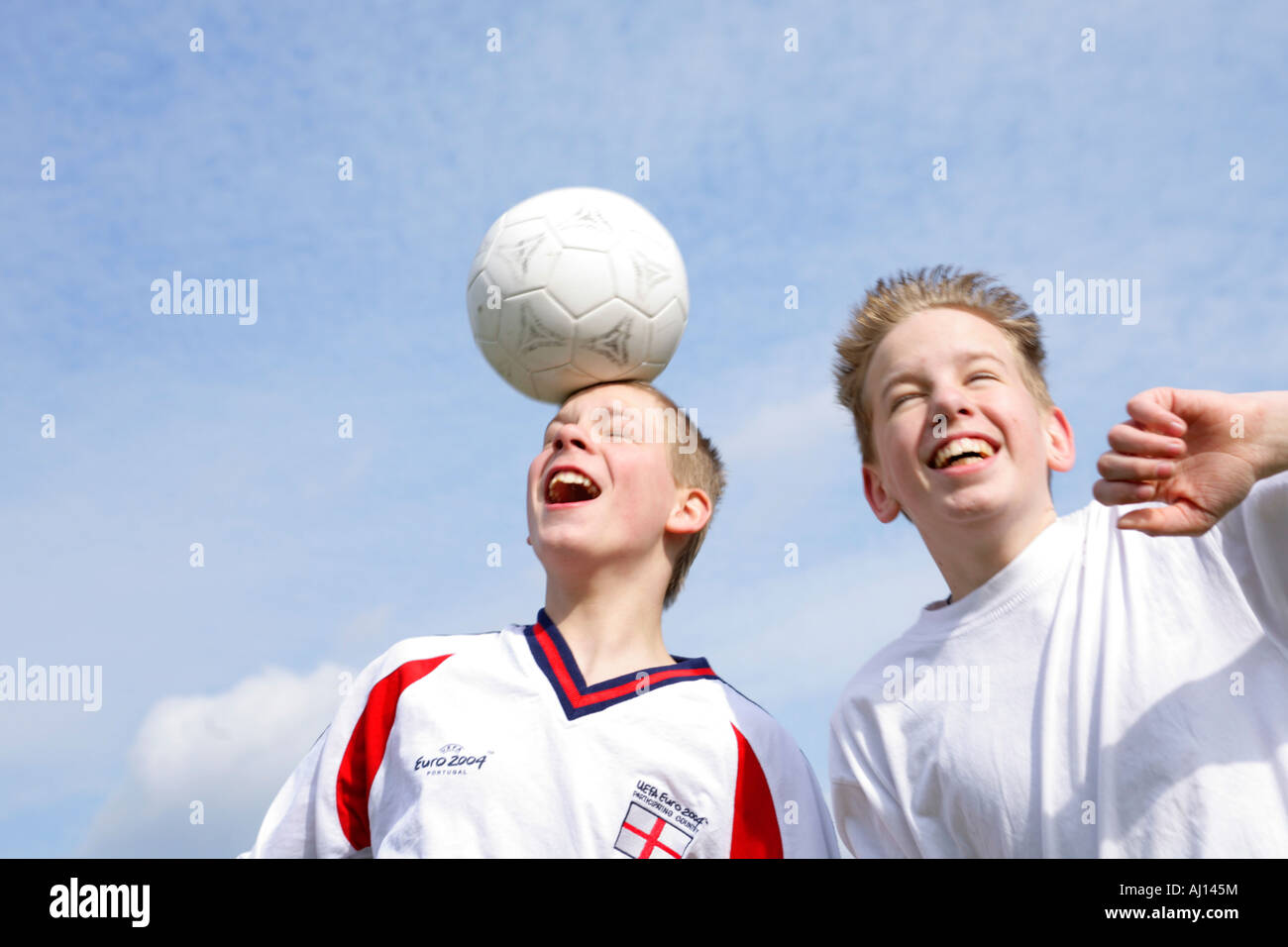 two teenage boys trying to head a ball Stock Photo - Alamy