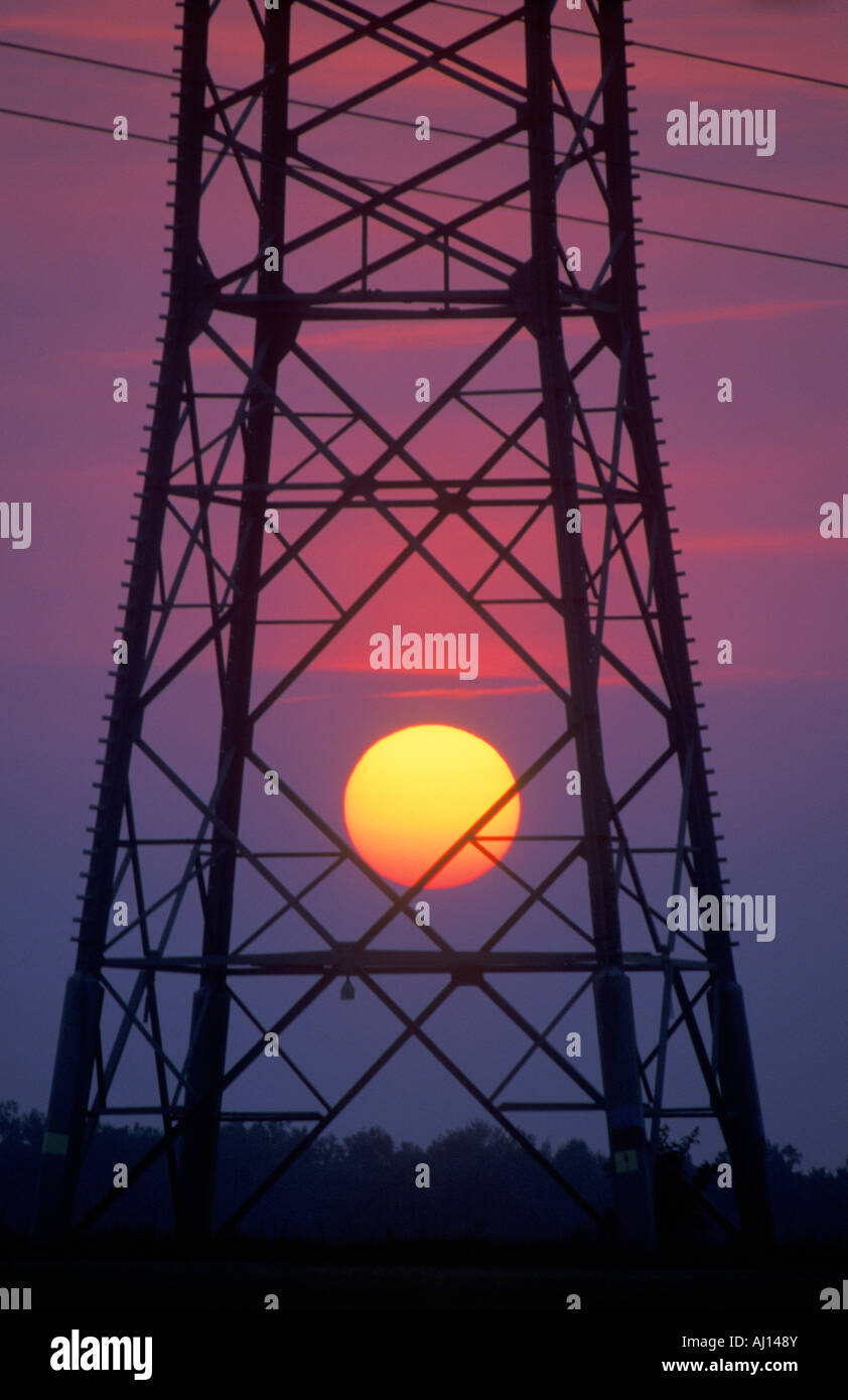 orange sun setting behind a pylon Stock Photo - Alamy