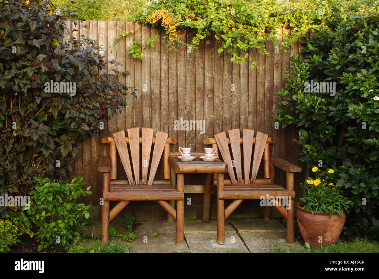 Two wooden garden seats with a table Stock Photo - Alamy
