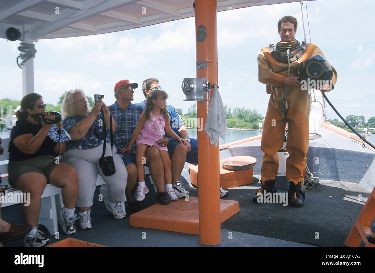 Greek sponge diver talks to tourists on boat in historic diving suit in ...