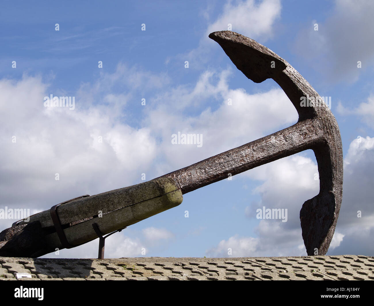 Side view of a large iron anchor. puffy white clouds and blue sky in ...