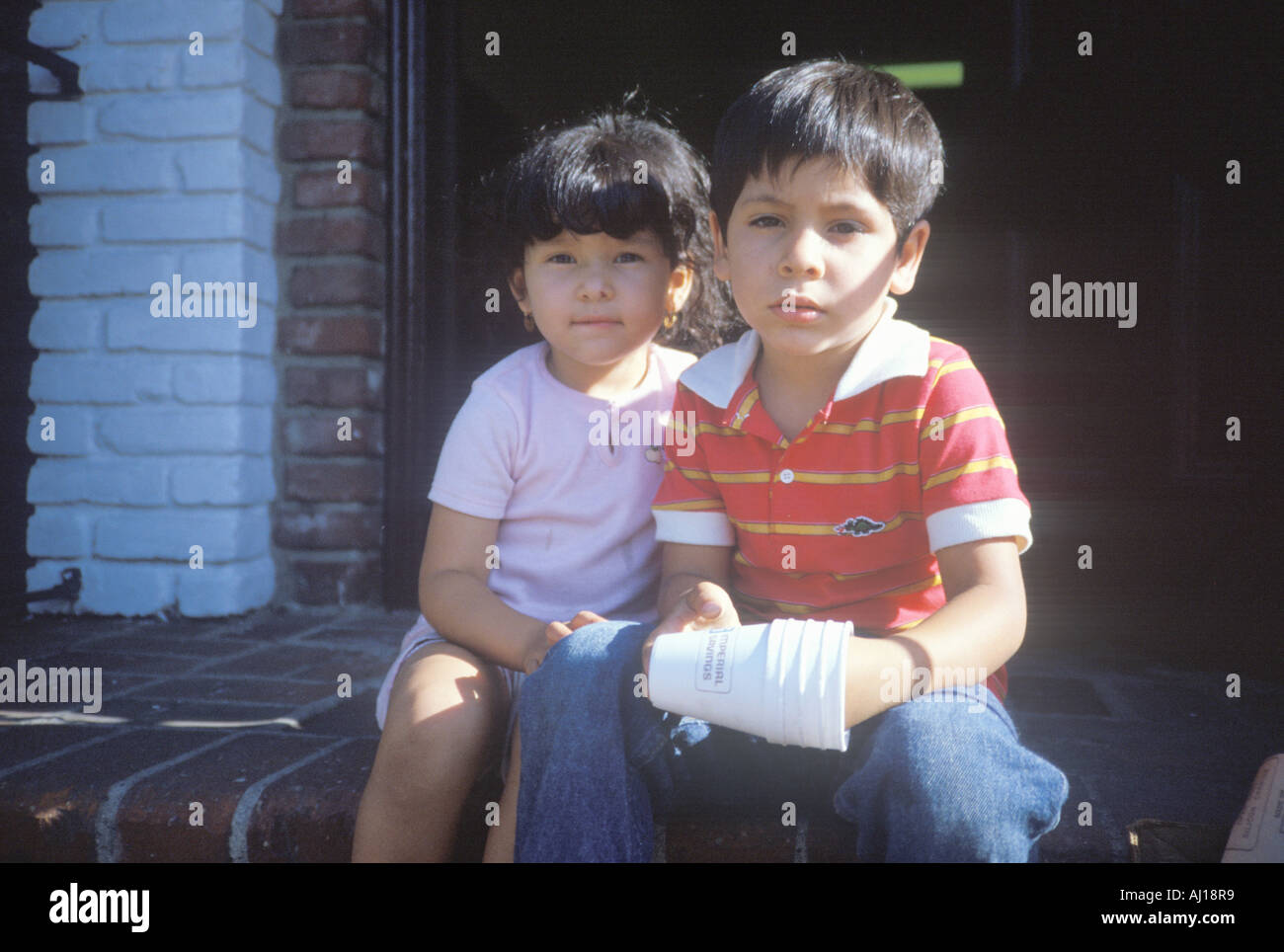 A Mexican brother and sister sitting on their front steps CA Stock ...