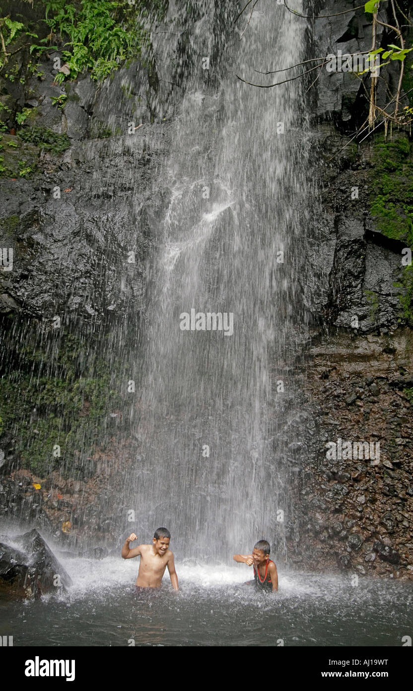 Young native boys play in cascading spray of Sipyen Waterfall in Kosrae ...