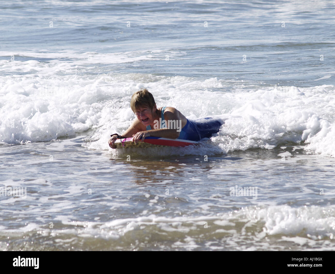 Old woman body boarding Stock Photo - Alamy
