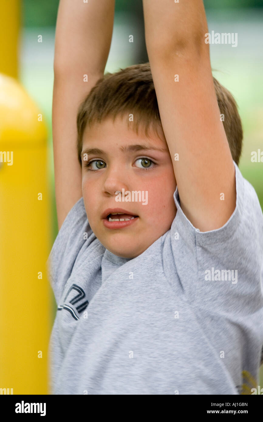 Boy hanging from jungle gym Stock Photo - Alamy