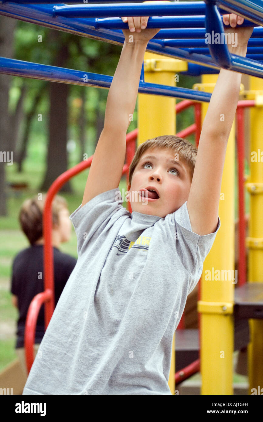 Young boy using overhead ladder on a jungle gym in a playground Stock ...