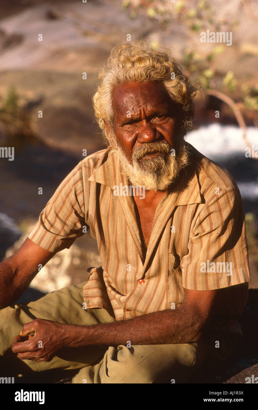 Portrait of aboriginal man, sitting by the river of his homeland. This ...