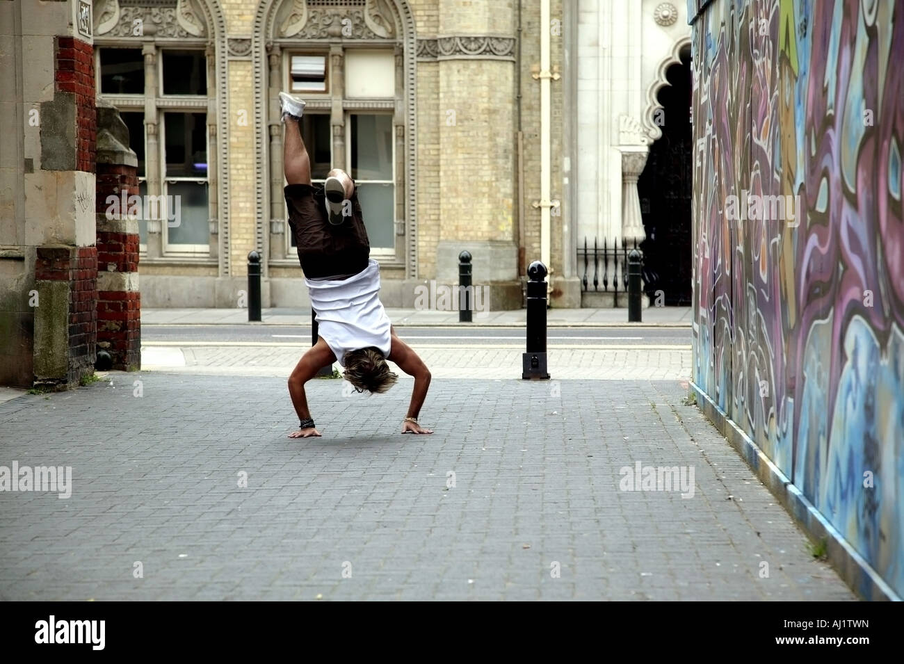 Man in summer attire doing a handstand next to a graffiti wall Stock ...