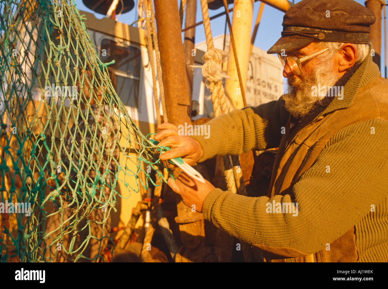 fisherman repairing nets Stock Photo - Alamy