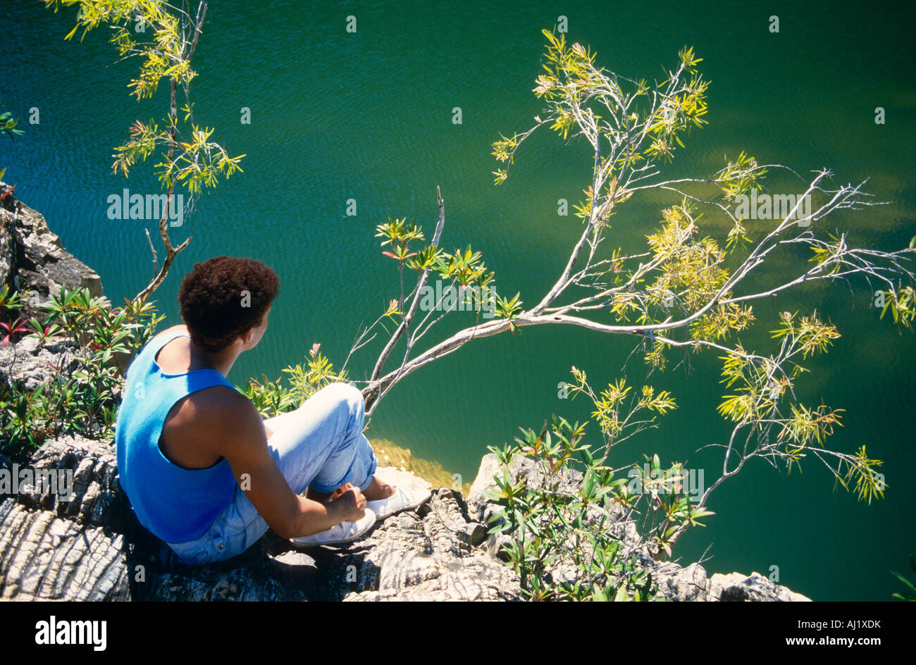 young man sitting in sun on riverbank looking into water Stock Photo ...