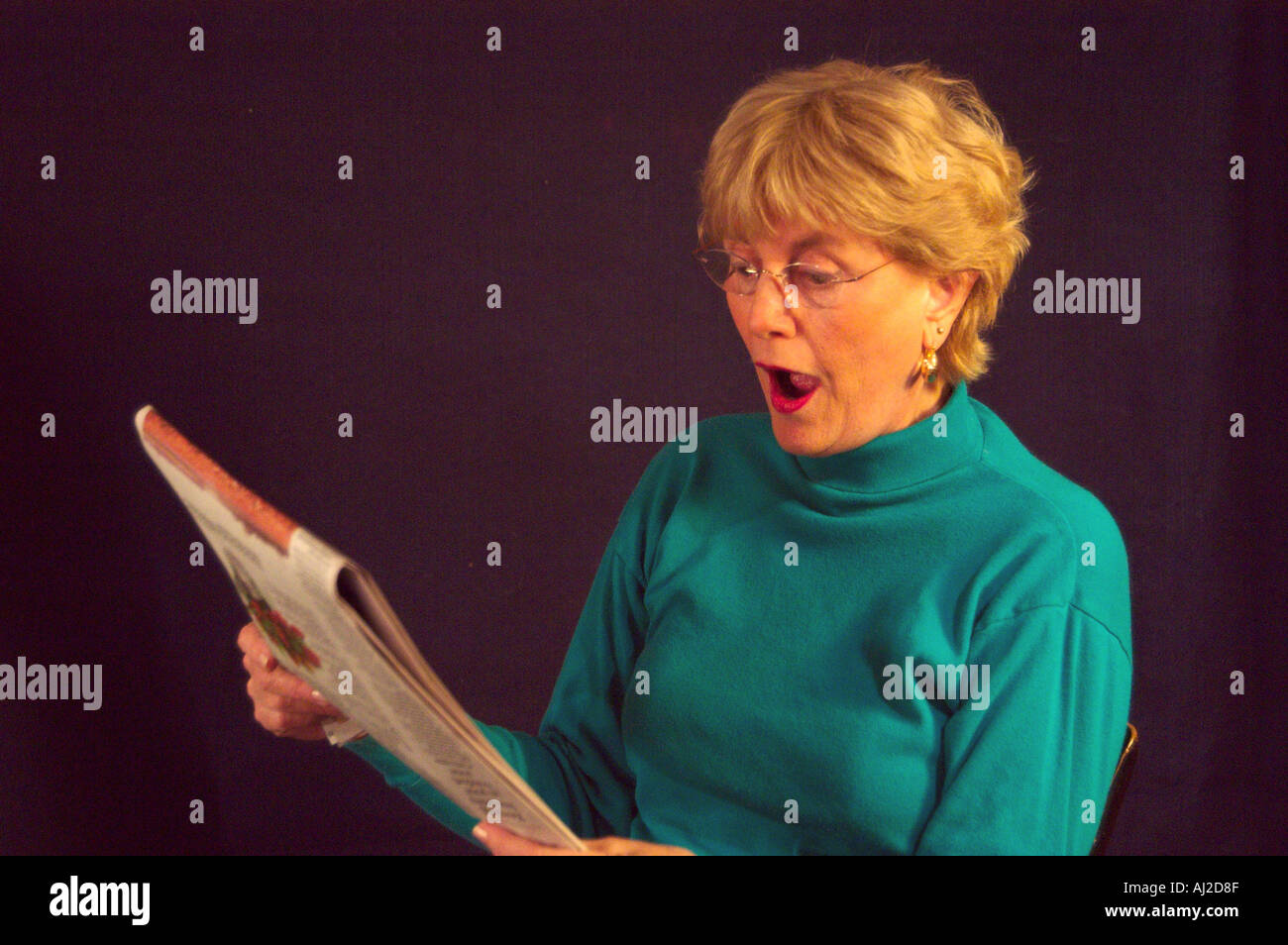 Senior woman reading newspaper with surprised expression Stock Photo ...