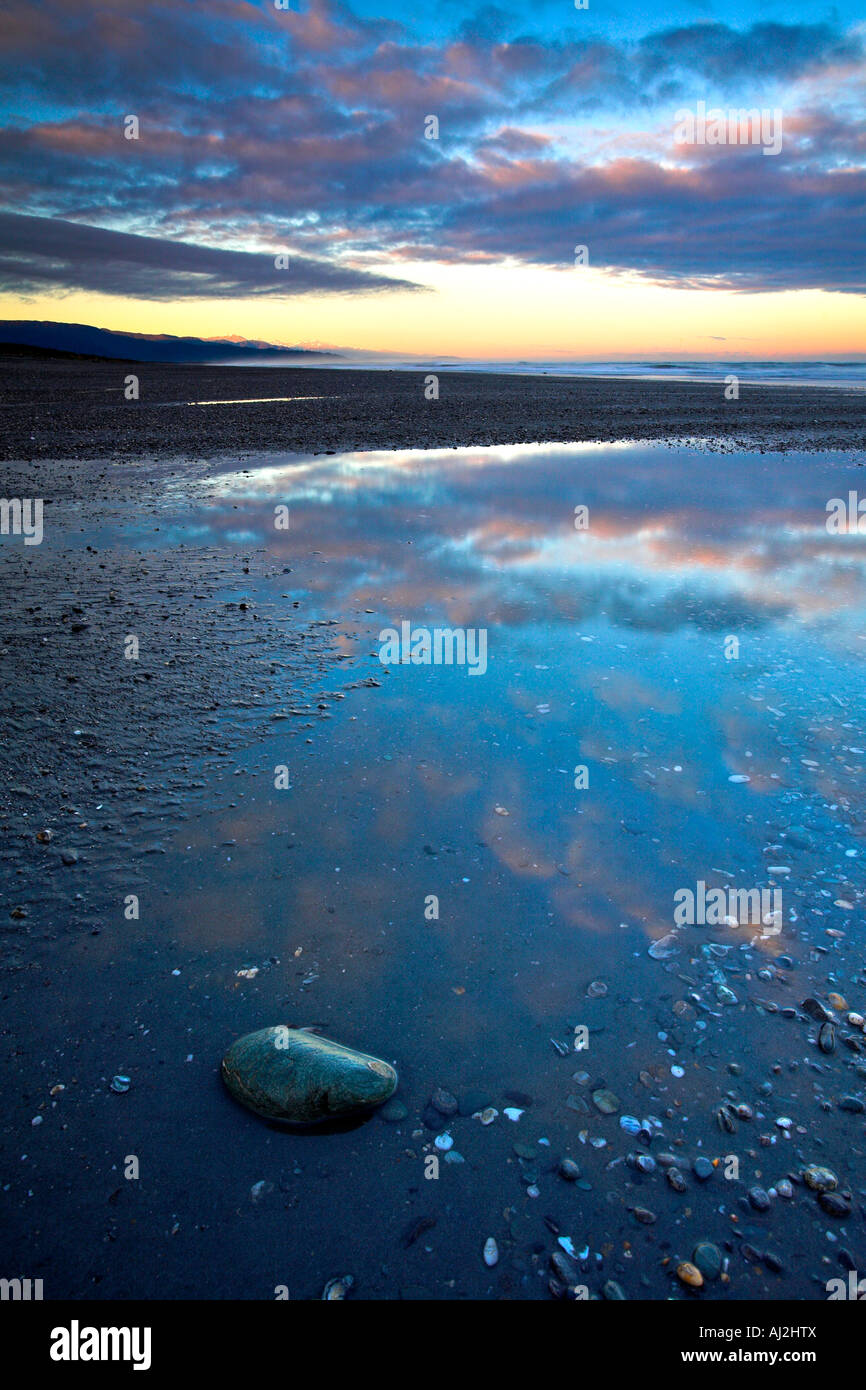 A remote west coast beach at dawn the sunrise glistening on the ...