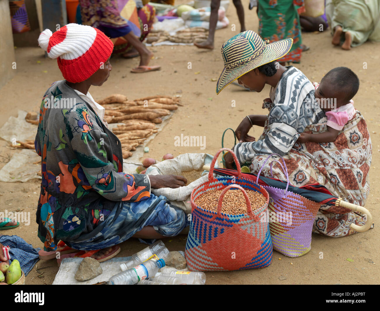 A Malagasy woman with her baby daughter on her back buys food from a ...