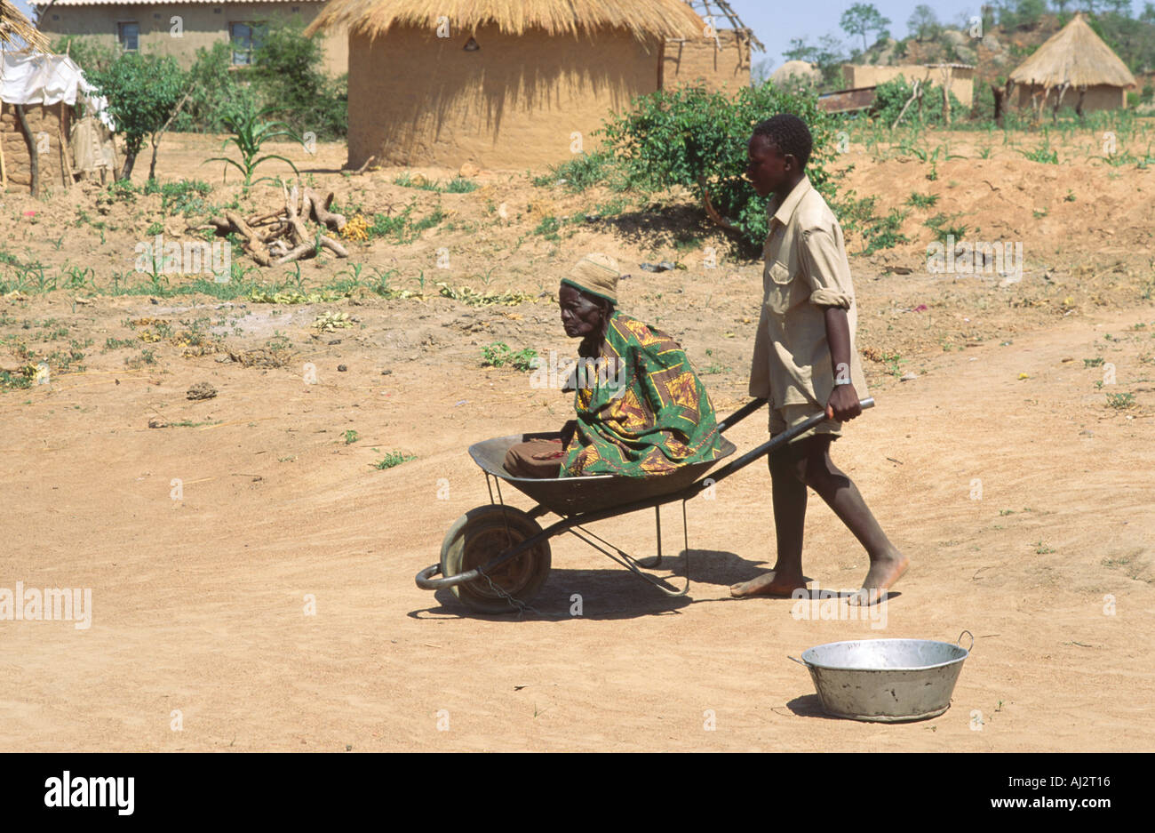 Young boy taking his elderly and infirm grandmother to the market in a ...