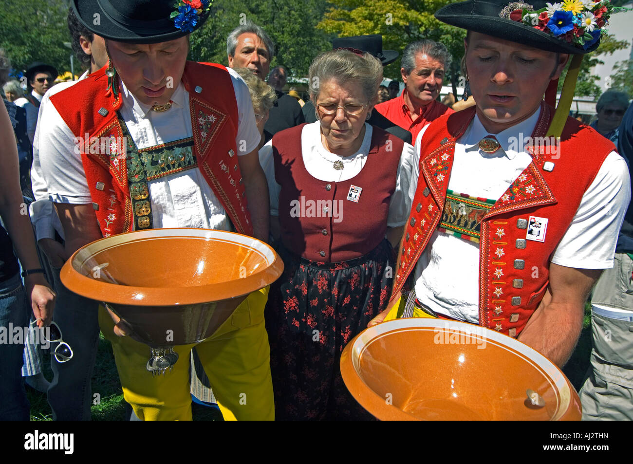 Cow bell ringers in traditional alpine costume practising coin spinning ...