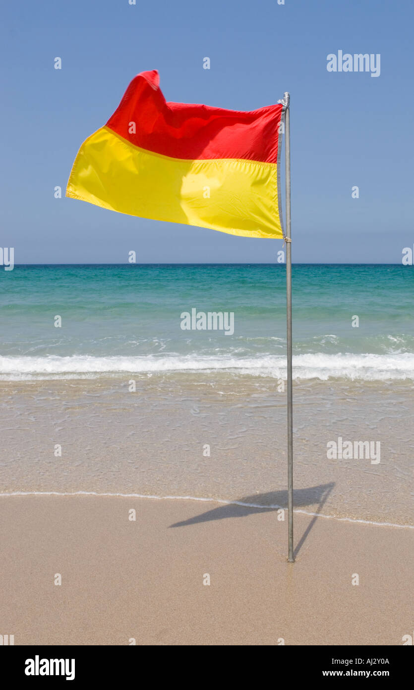 A two colour safety flag flapping in the wind on the beach at Sennen ...