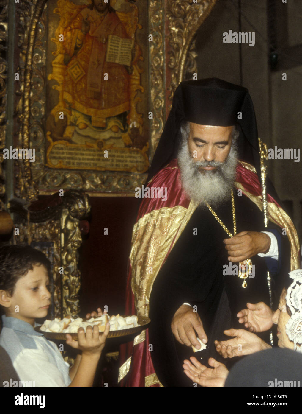 Greek Orthodox priest distributing wafers at Christmas communion in the ...