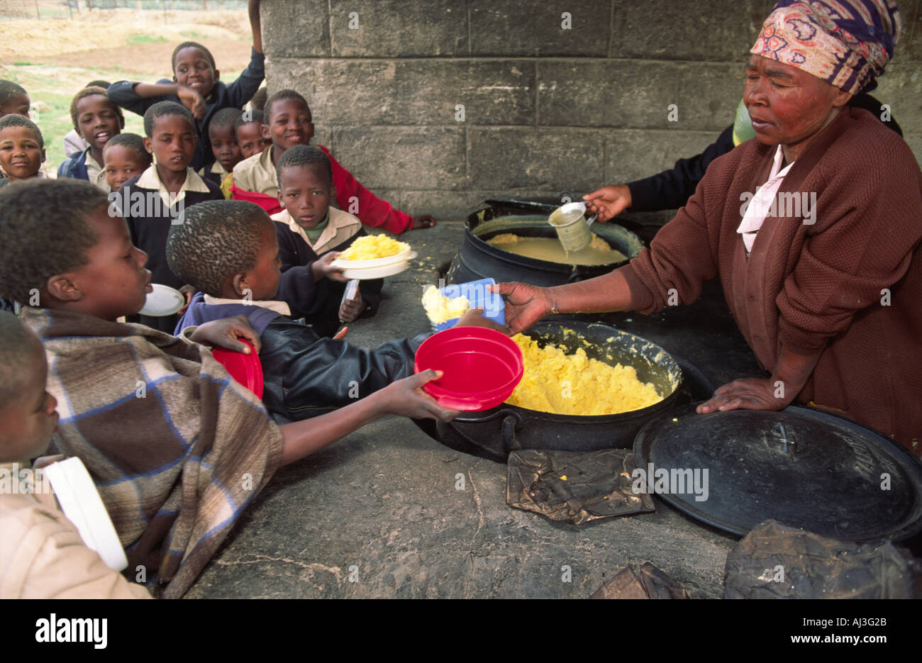 A cook serving the children a free mealie meal dinner at a rural school ...