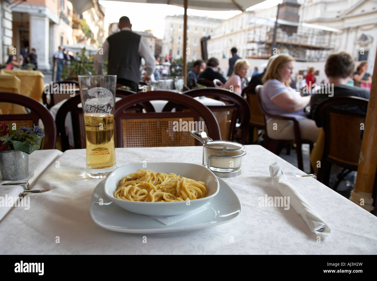 Bowl of Spaghetti Carbonara glass of beer and small bowl of parmesan ...