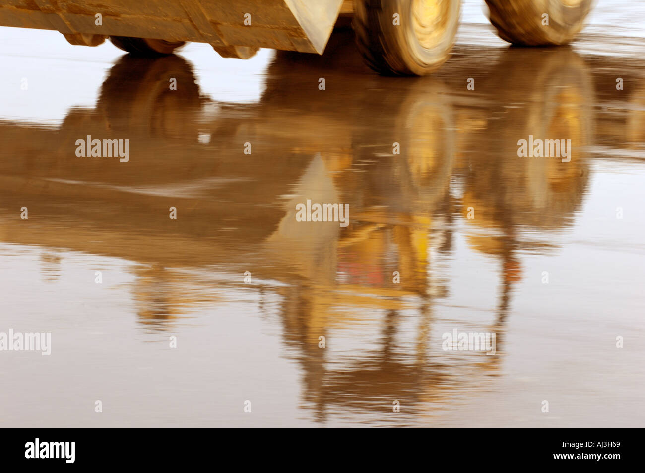Bulldozer rolling by with reflections on wet pavement Stock Photo - Alamy