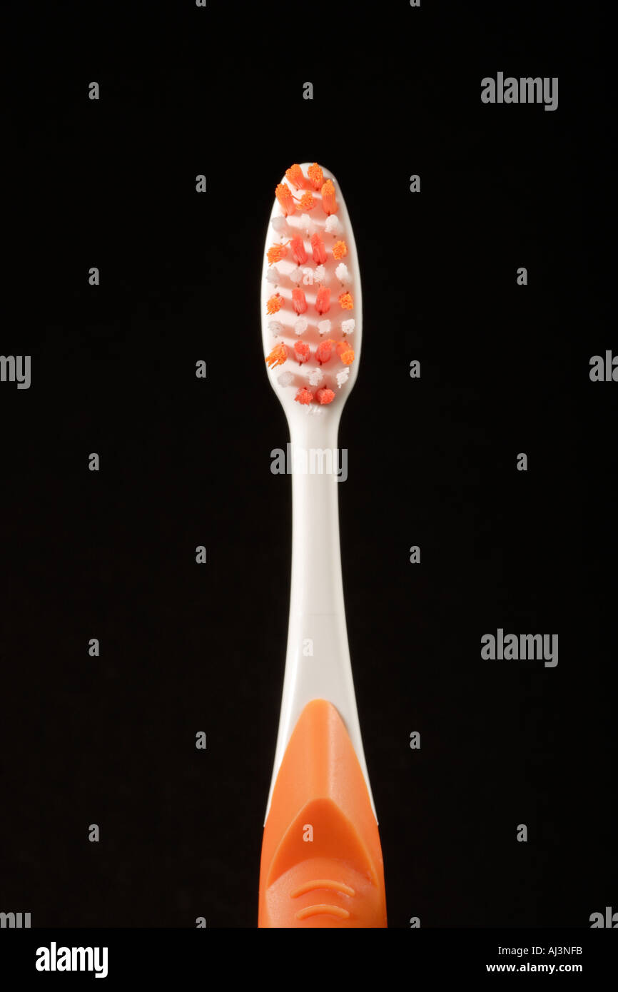 Orange toothbrush upright standing against black background Stock Photo ...