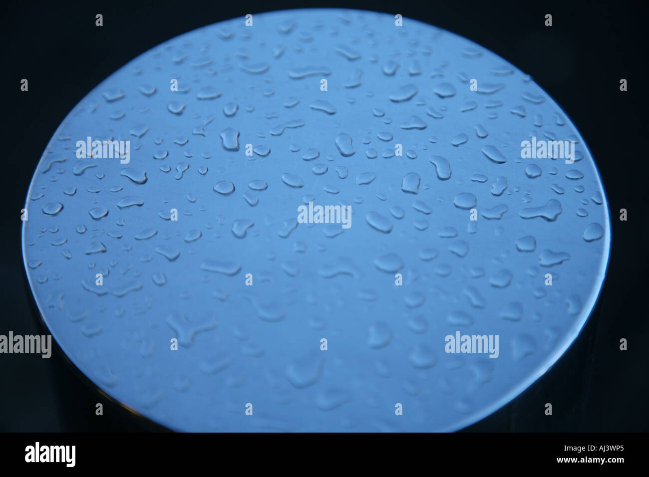 water droplets lay on a circular metal surface surrounded by black ...