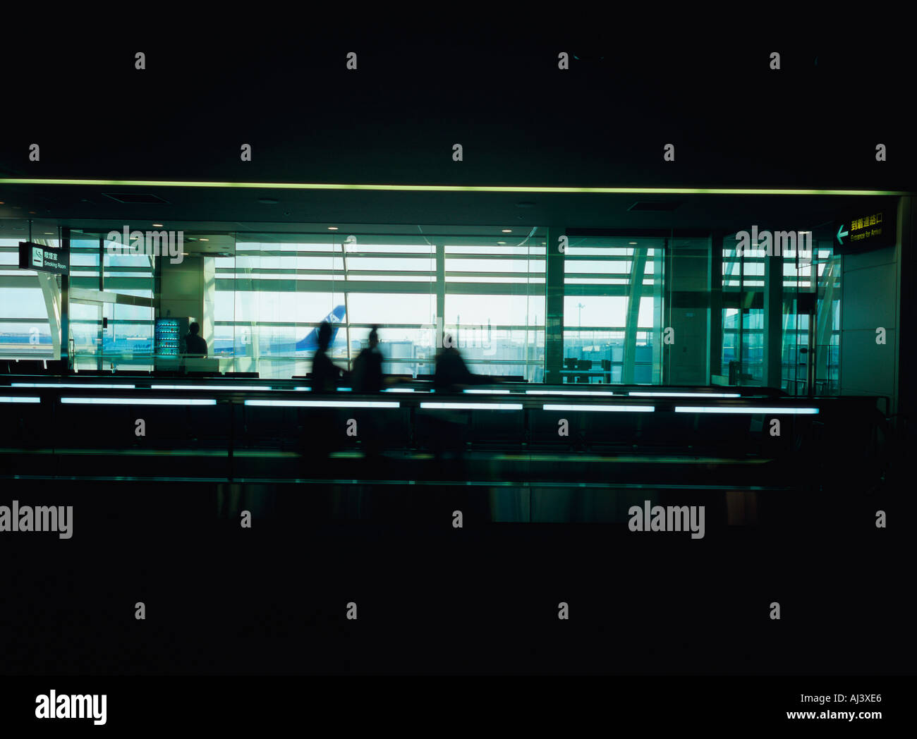Three people on moving walkway Stock Photo - Alamy