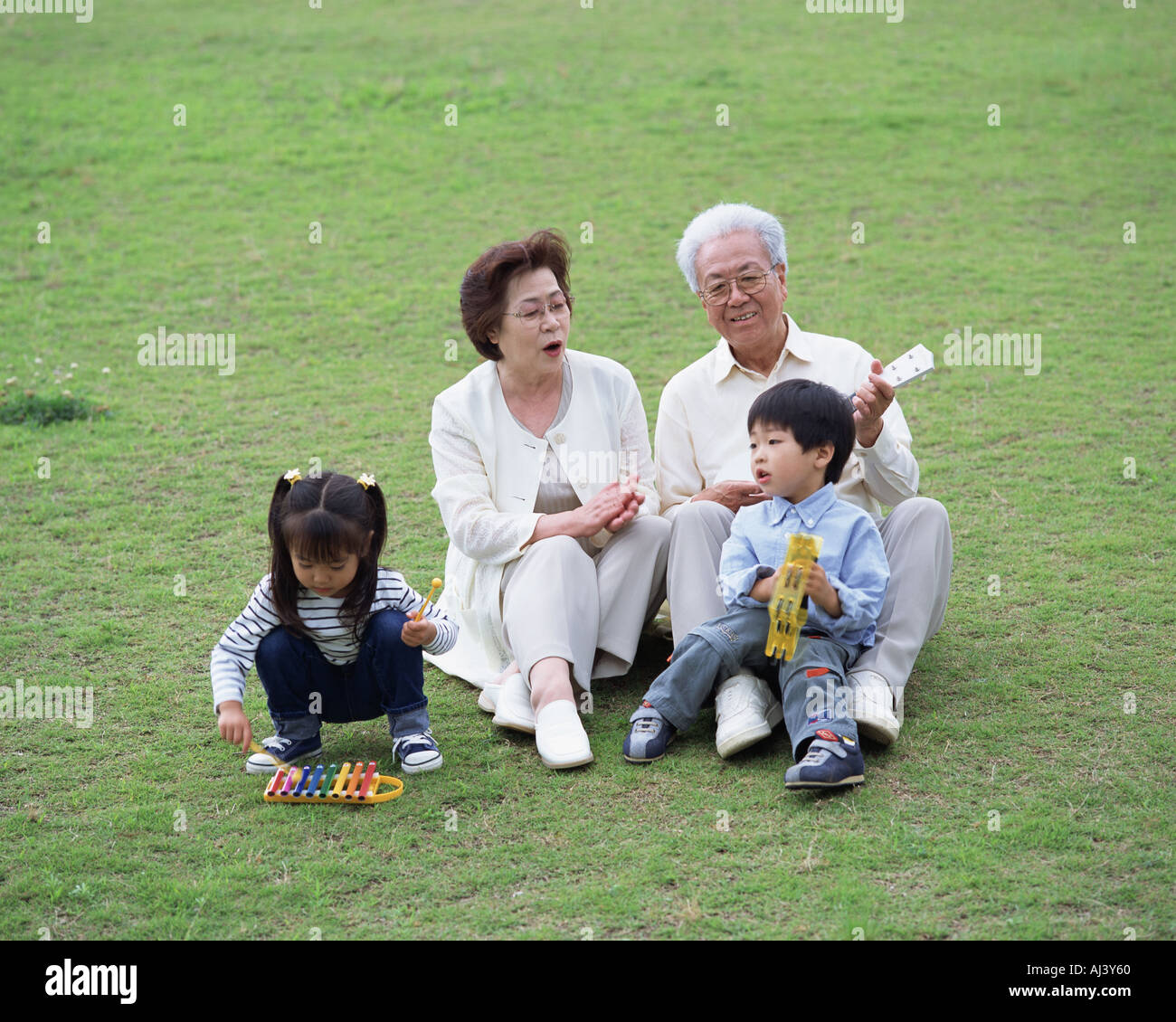 Senior couple playing with grand children in a park Stock Photo - Alamy