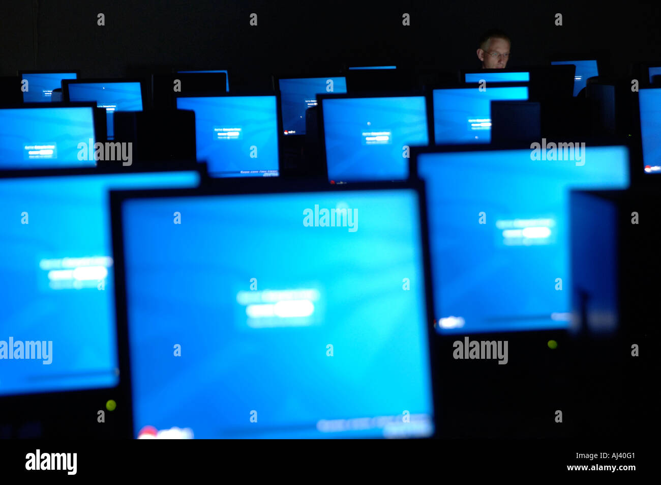 Computer terminals with man working late by himself Stock Photo - Alamy